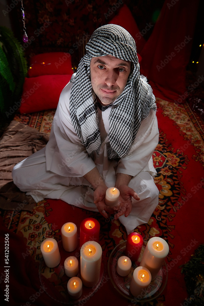 Arab sheikh in a white robe and a headscarf in a boudoir in a room with ...