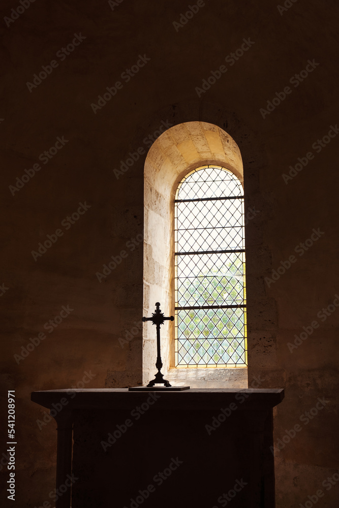 Cross silhouette on altar near window in dark empty old chapel. Game of ...