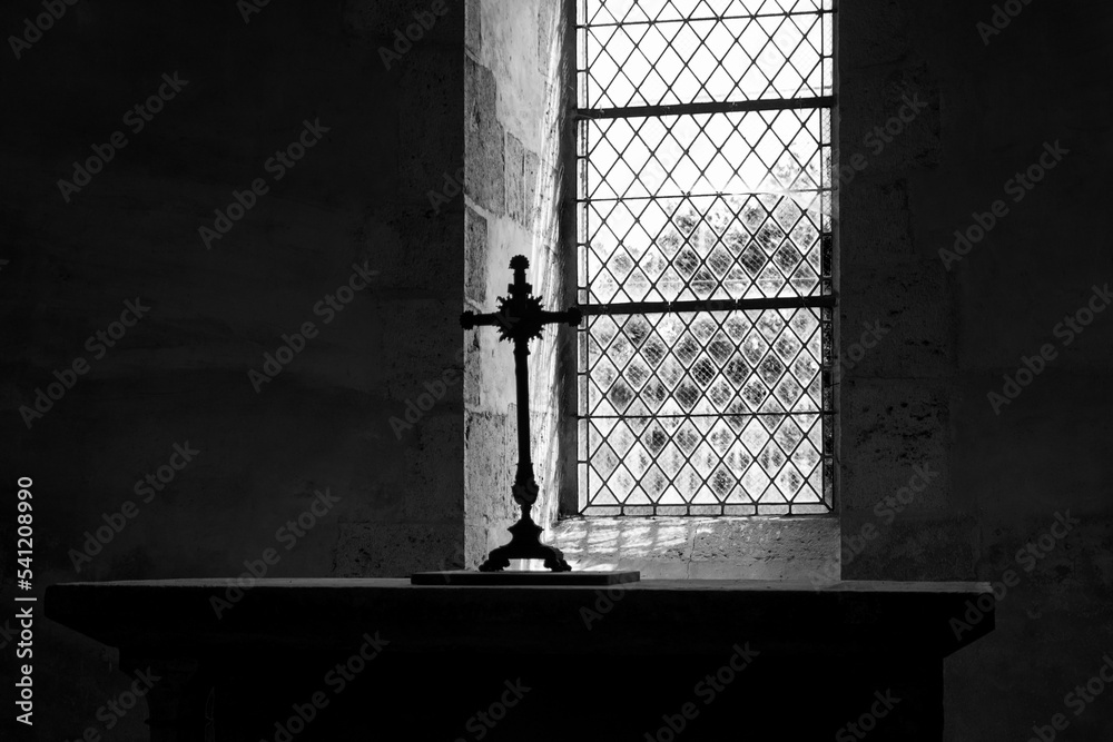 Cross silhouette on altar near window in dark empty old chapel. Game of ...