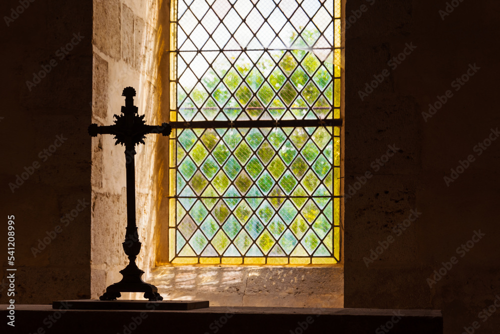 Cross silhouette on altar near window in dark empty old chapel. Game of ...