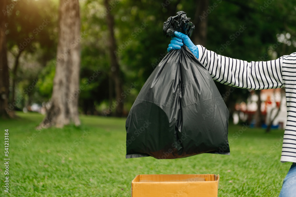 Hand holding garbage black bag putting in to trash to clean. Clearing ...