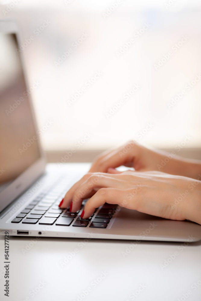 The girl behind the laptop. Female hands typing text on the keyboard ...