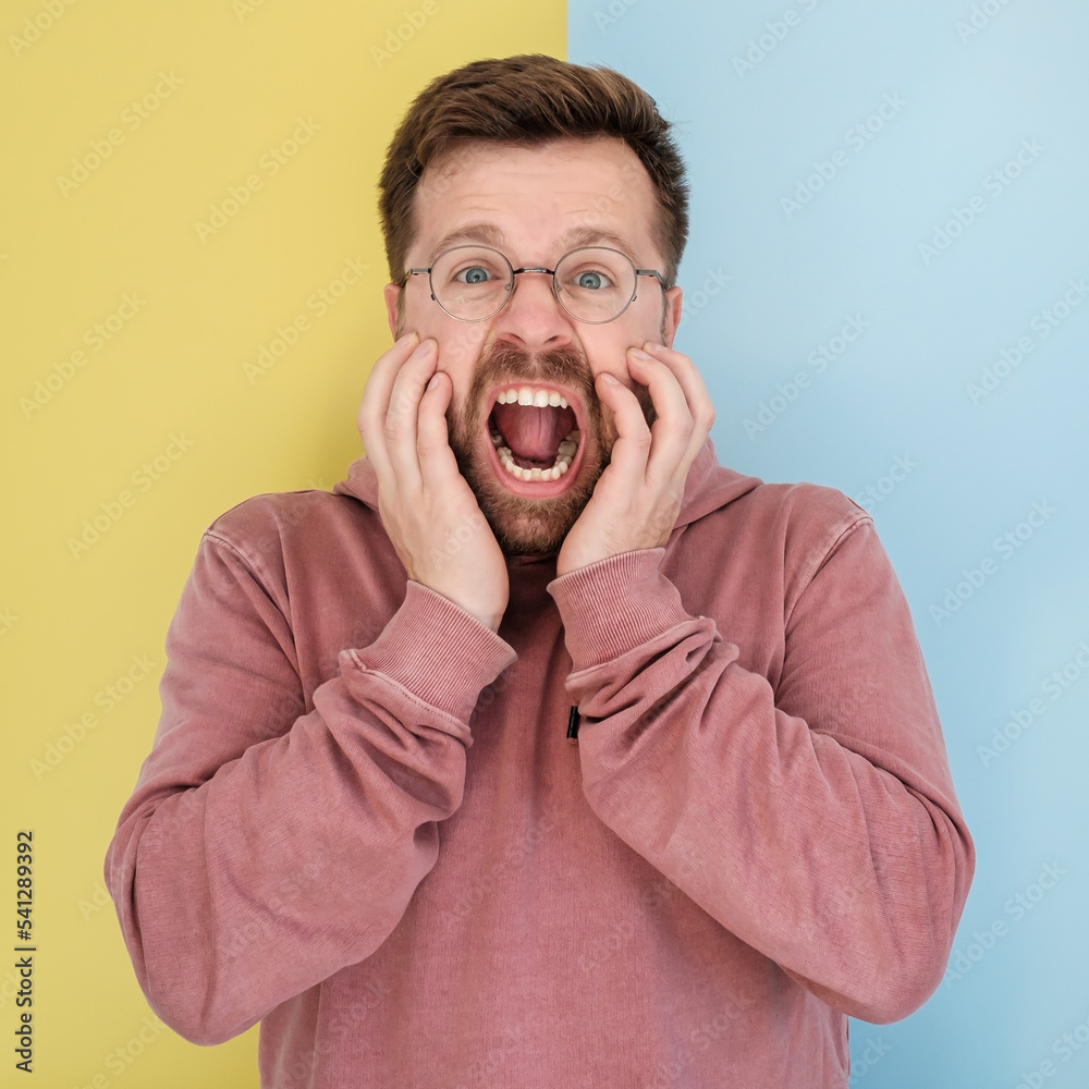 Man is stressed and screaming loudly, standing on a yellow-blue ...