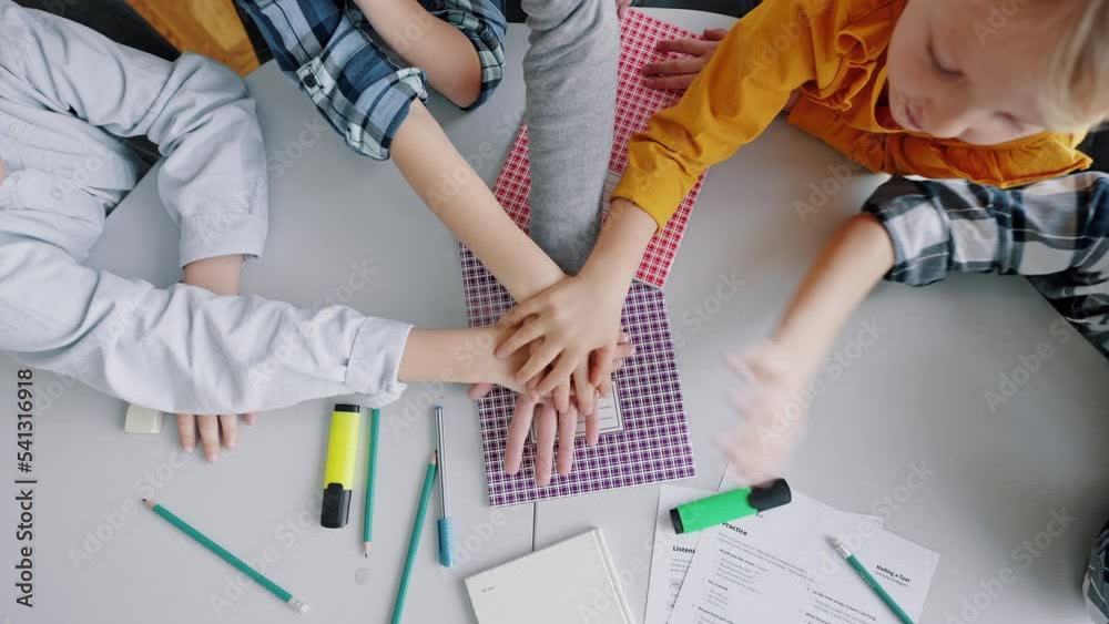 Teacher and pupils put hands in gesture of team unity Stock Video ...