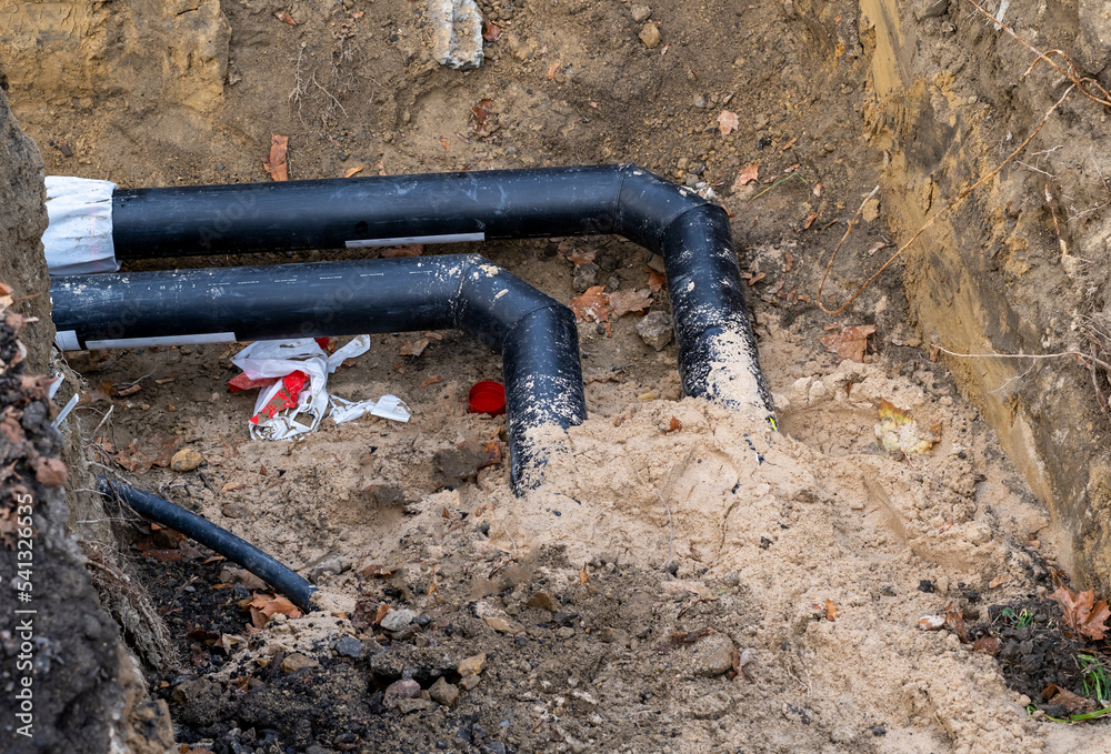 Black pipes in the ground and sand. Installation of sewer pipes in the ...