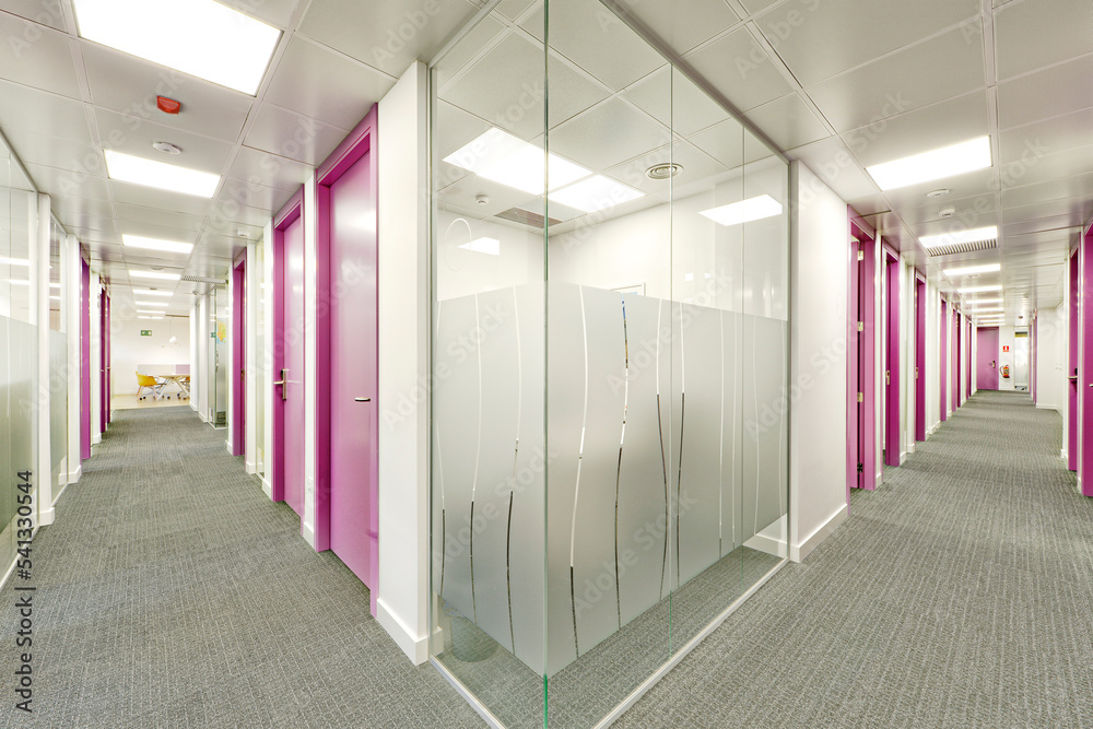 Crossing of office corridors with glass cubicles and gray carpeted ...
