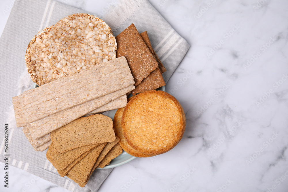 Rye crispbreads, rice cakes and rusks on white marble table, flat lay ...