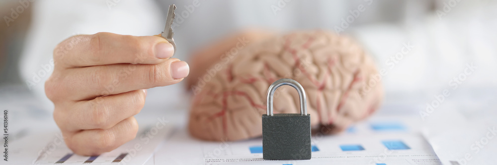 Woman hold key, lock and human brain on desk, symbol as key to someones ...