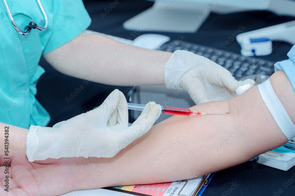 Doctor or nurse hand in white nitrile glove was using syringe to draw ...