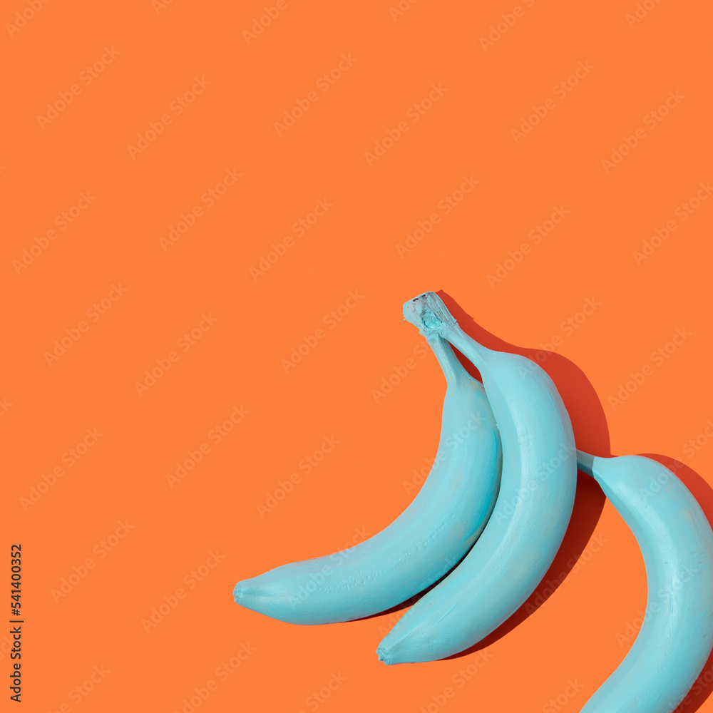 Creative layout with pastel blue bananas on bright orange background ...