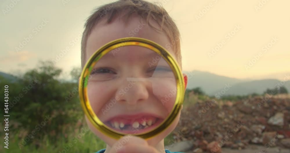 Portrait happy cute smiling child looking at camera with magnifying ...