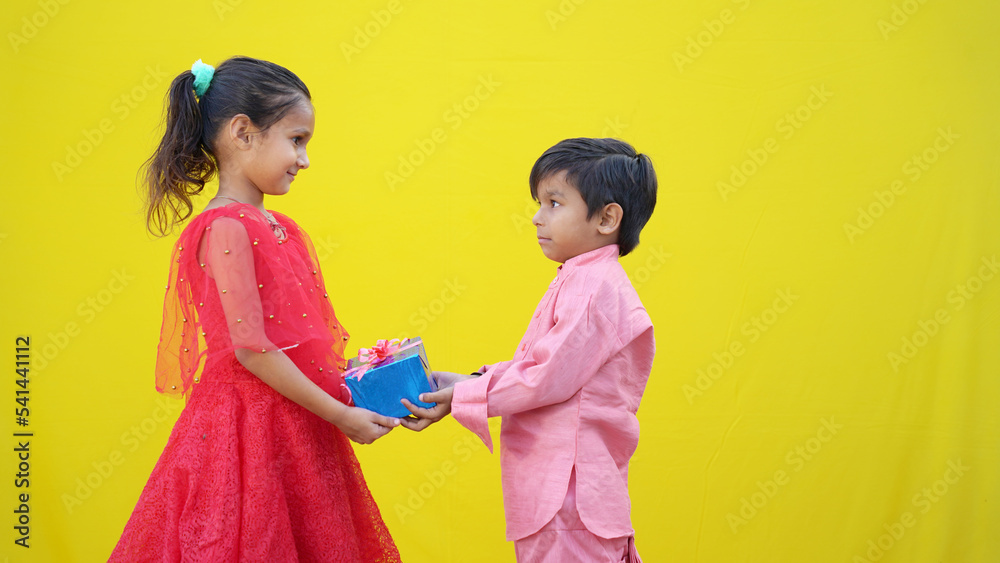 Happy little child boy gives smiling girl a gift box, making a surprise ...