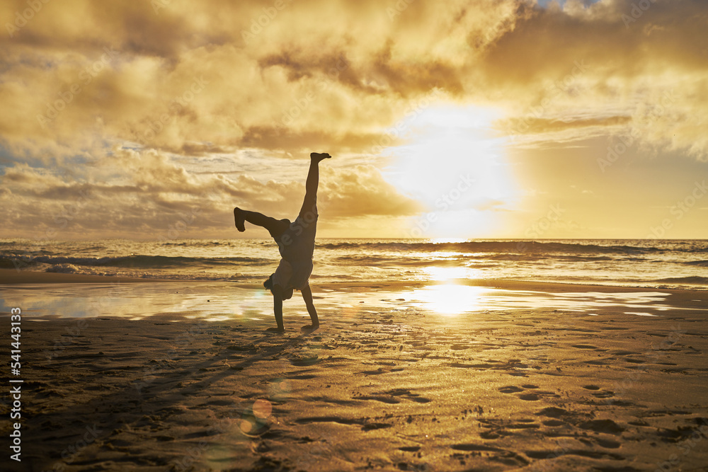 Sunset, silhouette and child doing cartwheel at the beach having fun ...