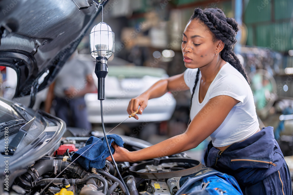 Mechanical girl at car repair shop stand pulling engine oil dipstick to ...