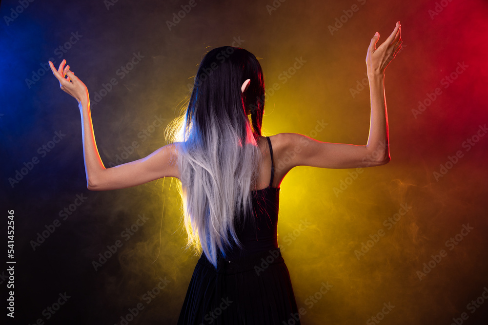 Rear back view of Elf queen in fantasy rope long dress cast spell ...