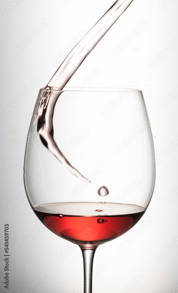 Copa de cristal con vino rosado, vertiendo vino en copa sobre fondo ...