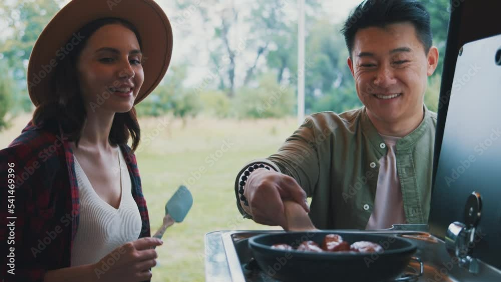 Horizontal view of romantic couple cooking together inside camper van ...