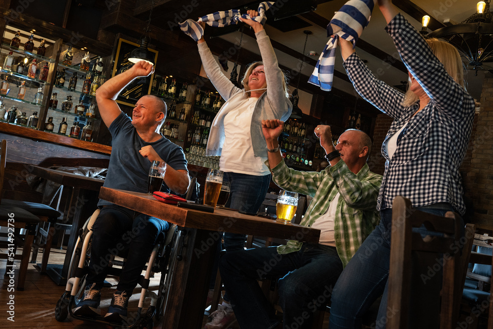 Senior football and soccer fans drinking beer at the pub, cheering and ...