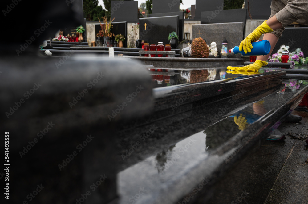 Foto de Headstone cleaning on cemetery. Professional in yellow gloves ...