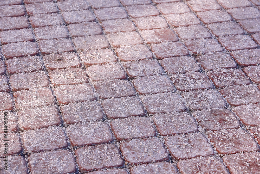 Salt grains on paving slabs in winter. Sprinkled salt on icy sidewalk ...