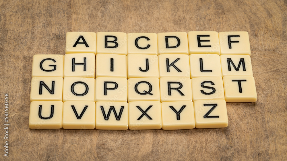 English alphabet in ivory letter tiles against textured handmade paper ...