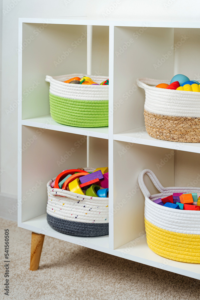 Colorful storage baskets on shelves. White shelving with rainbow wooden ...