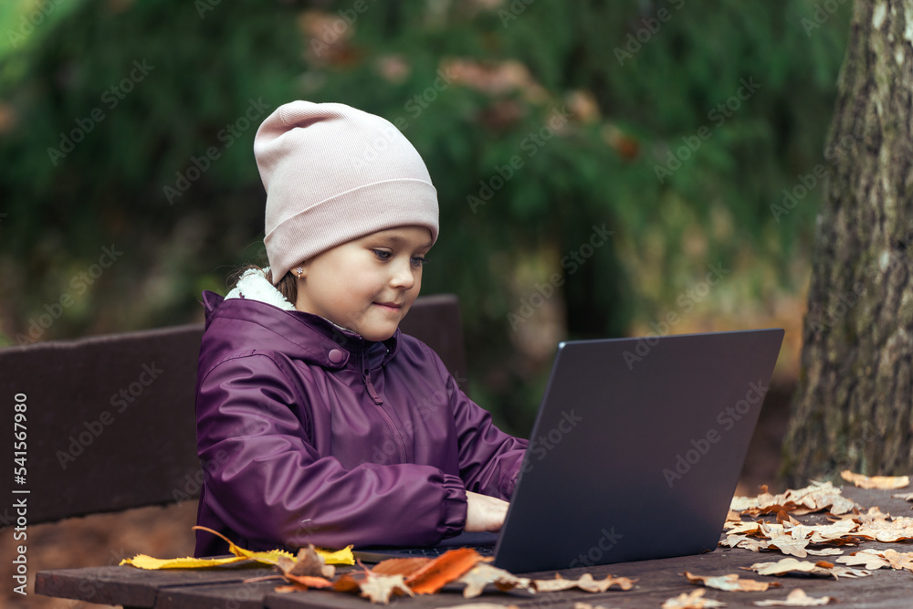 Cute little girl using a laptop computer for online learning at an old ...