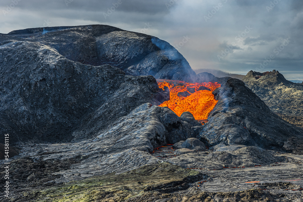 Lava flows from a volcanic crater. hot reddish liquid magma from the ...