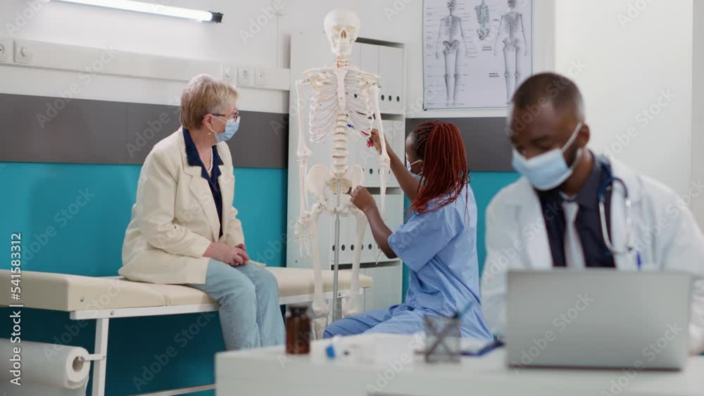 Old woman and nurse with face masks analyzing human skeleton bones at ...