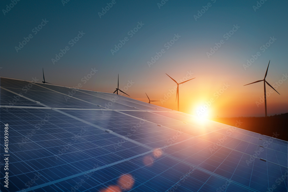 Solar panels with wind turbines against sunset sky background ...