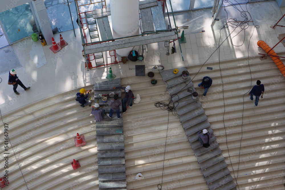 Workers install granite ladder on the unfinished building supermarket ...