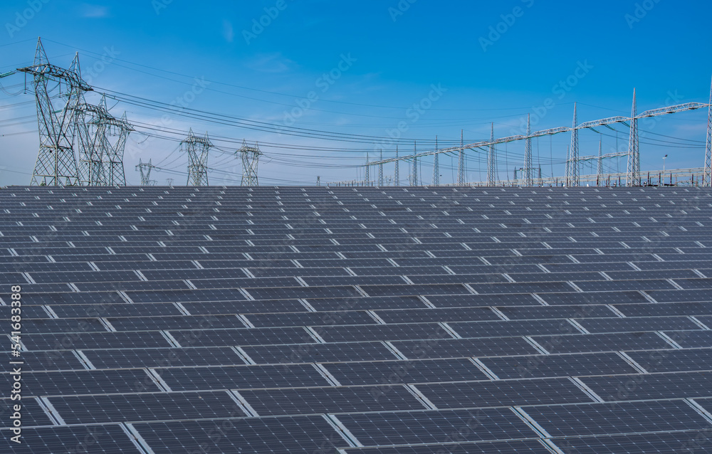 Solar panels with high voltage pylons on blue sky, electricity ...