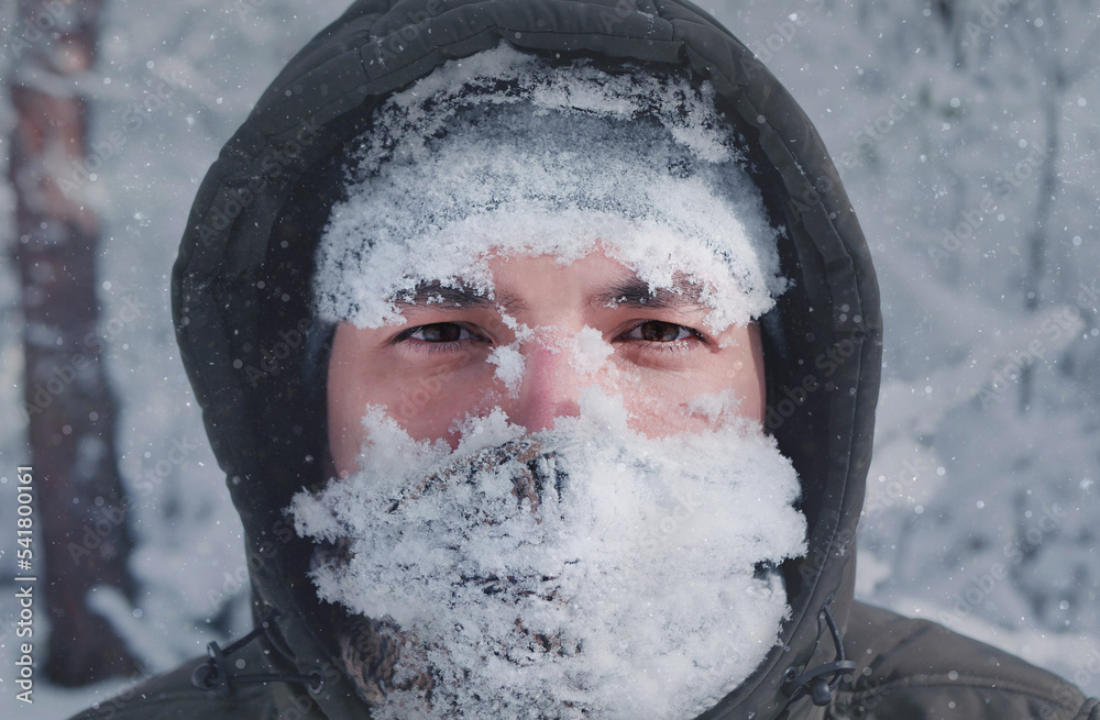 Man's face in the snow against the backdrop of a snowfall. Man in snow ...