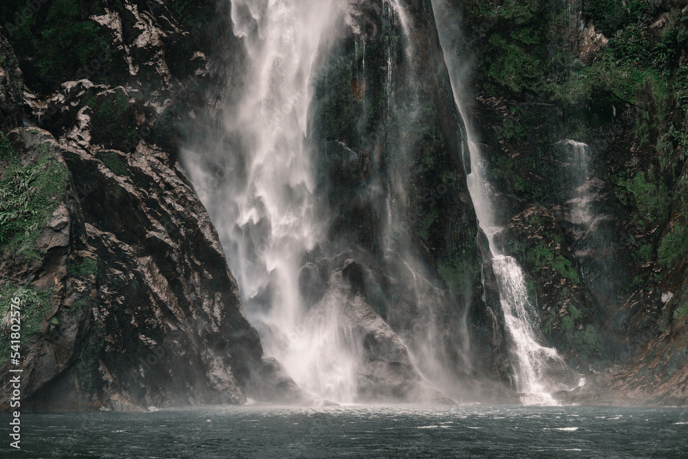 cascading water pouring down onto the calm calm blue lake waters in a ...