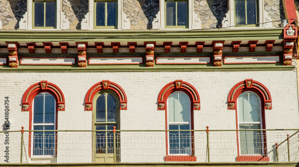 Old historic building windows. Windows are arched with ornate red trim ...