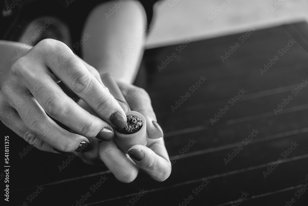 Foto de Hands with dark nails putting a weed bud in a marijuana plastic ...