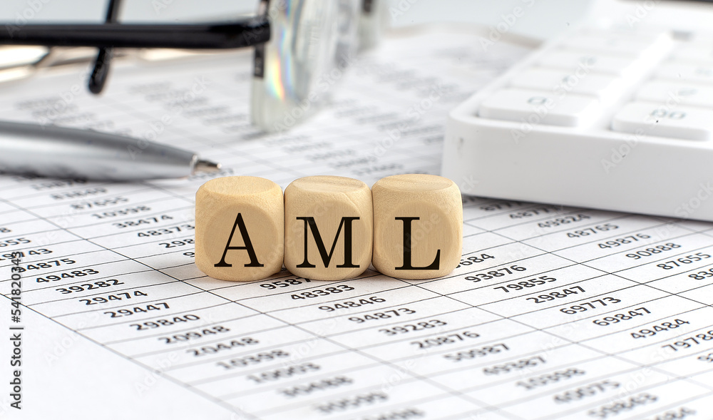 wooden cubes with the word AML on a financial background with chart ...