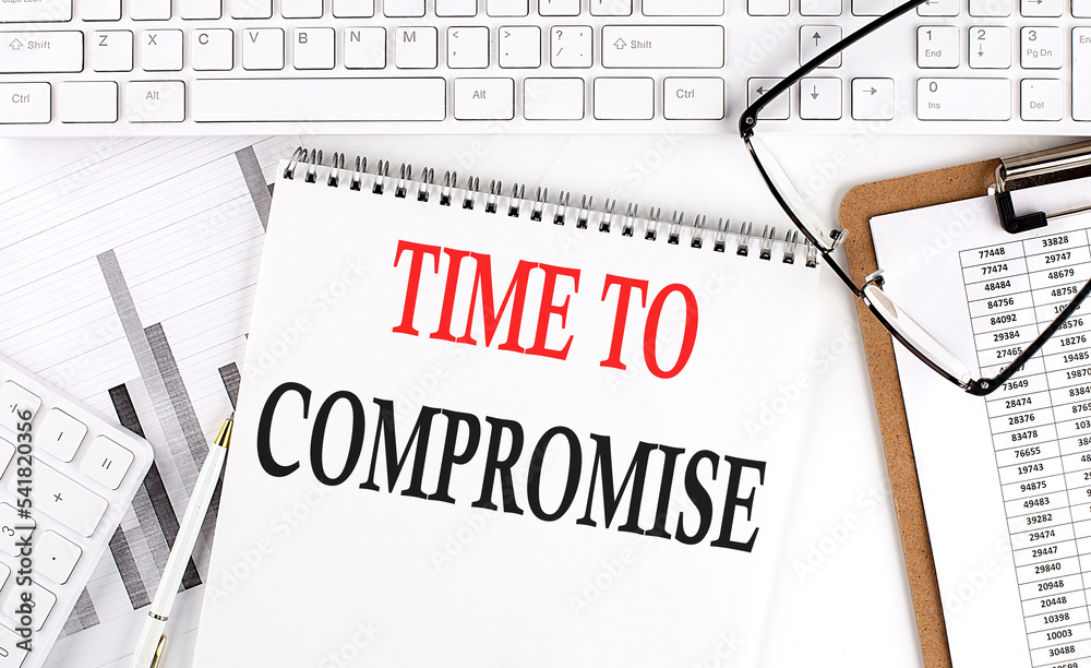 Text TIME TO COMPROMISE on Office desk table with keyboard, notepad and ...