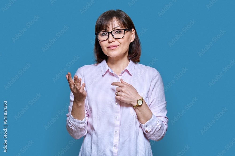 Talking gesturing woman looking at camera on blue studio background ...
