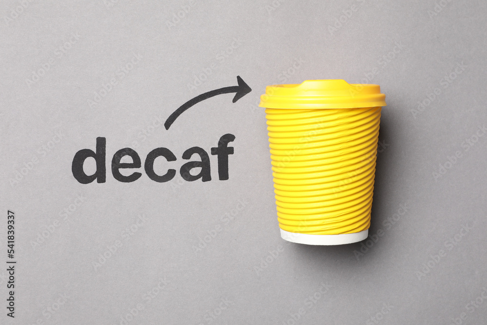 Word Decaf and arrow pointing at takeaway paper coffee cup on light ...