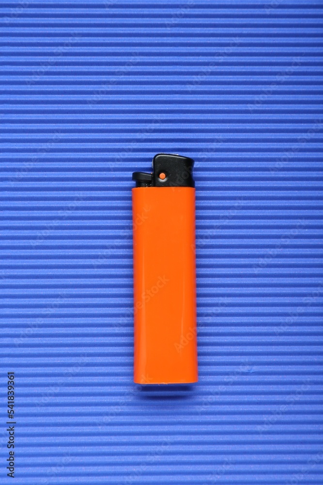 Stylish small pocket lighter on blue corrugated fiberboard, top view ...