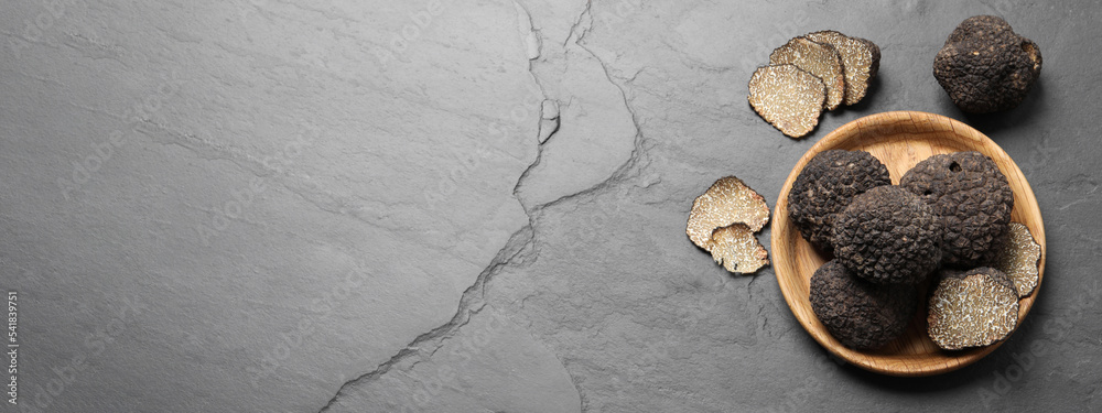 Black truffles on grey table, flat lay with space for text. Banner ...
