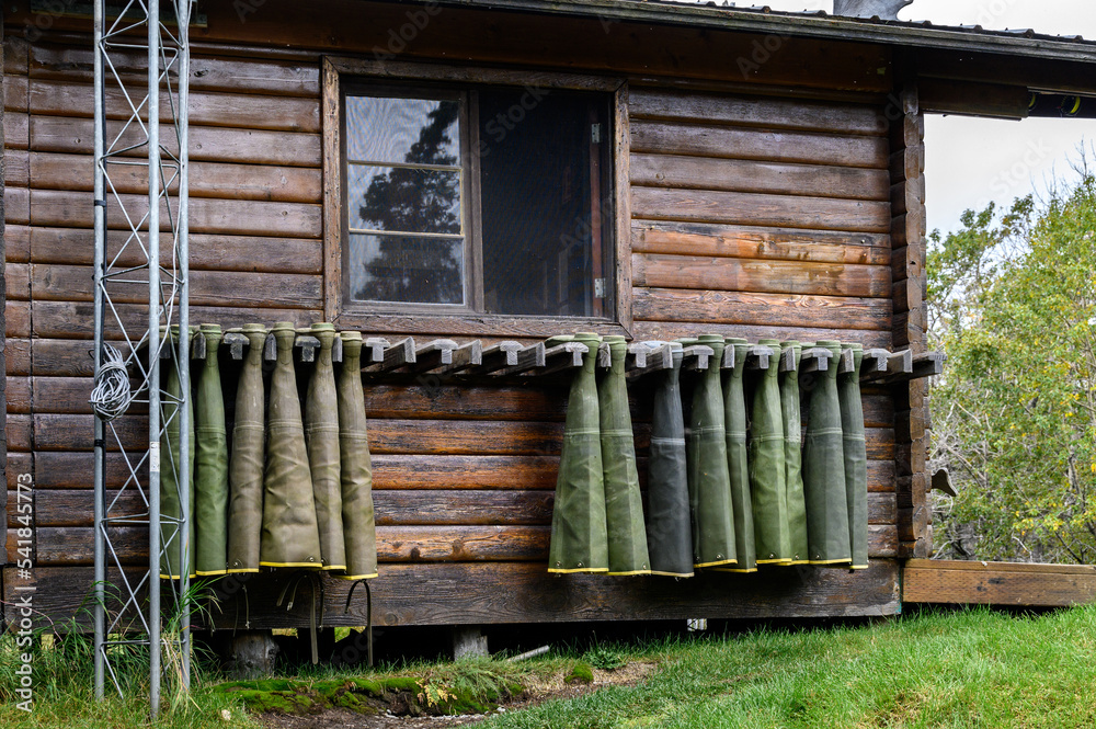 Collection of hip waders hanging up drying outside on a rustic wood ...