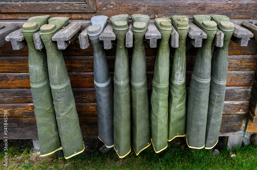 Collection of hip waders hanging up drying outside on a rustic wood ...