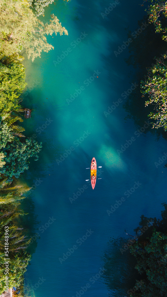 A couple of men and women are Kayaking in the rainforest of Koh Chang ...