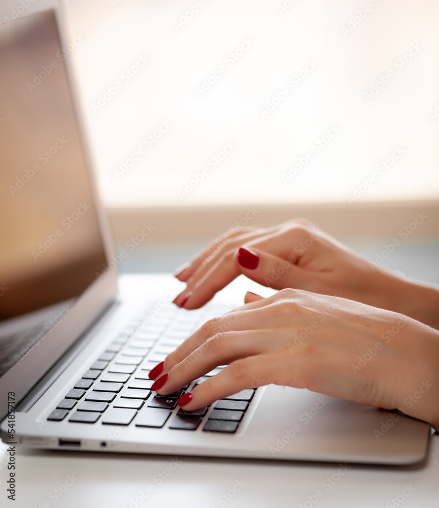 The girl behind the laptop. Female hands typing text on the keyboard ...