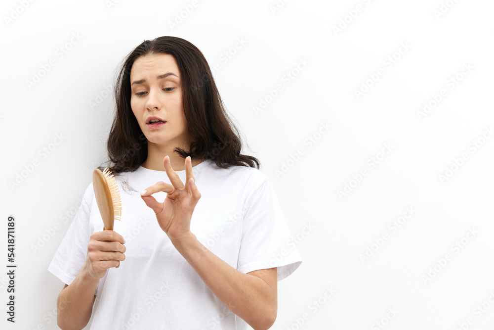 a funny, emotional, sad woman stands in a white T-shirt on a white ...