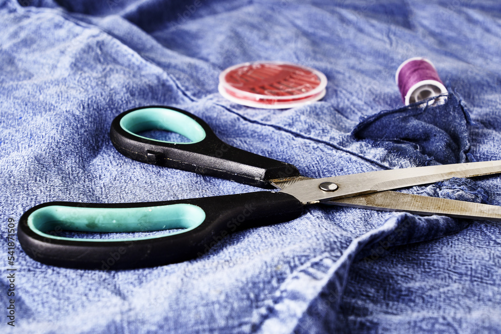 scissors needles and thread on the background of torn jeans concept ...