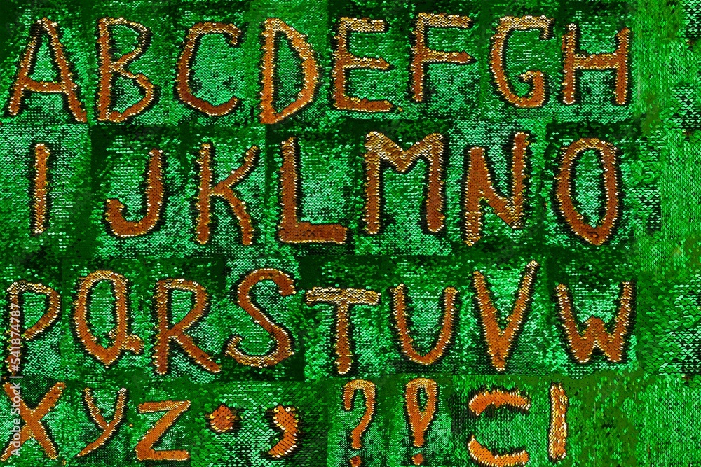 Alphabet sequins. Golden sequins letters on green sparkling sequins ...