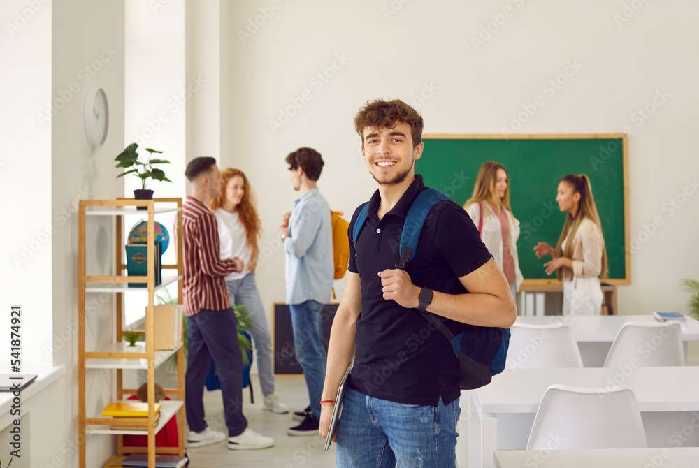 Smiling guy student with bag in audience looking at camera during break ...
